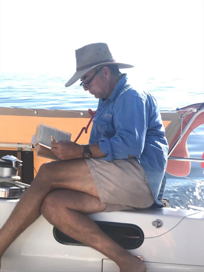 The Captain hard at work on passage, eating anzac biscuits and reading ...